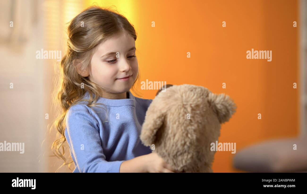 Preschool girl looking at teddy bear, playing with toy, happy little ...