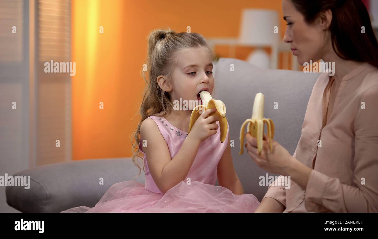 Beautiful little princess and mommy eating bananas, healthy snacks ...