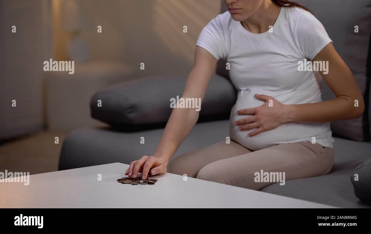 Crying unhappy pregnant lady counting coins on table and touching belly ...