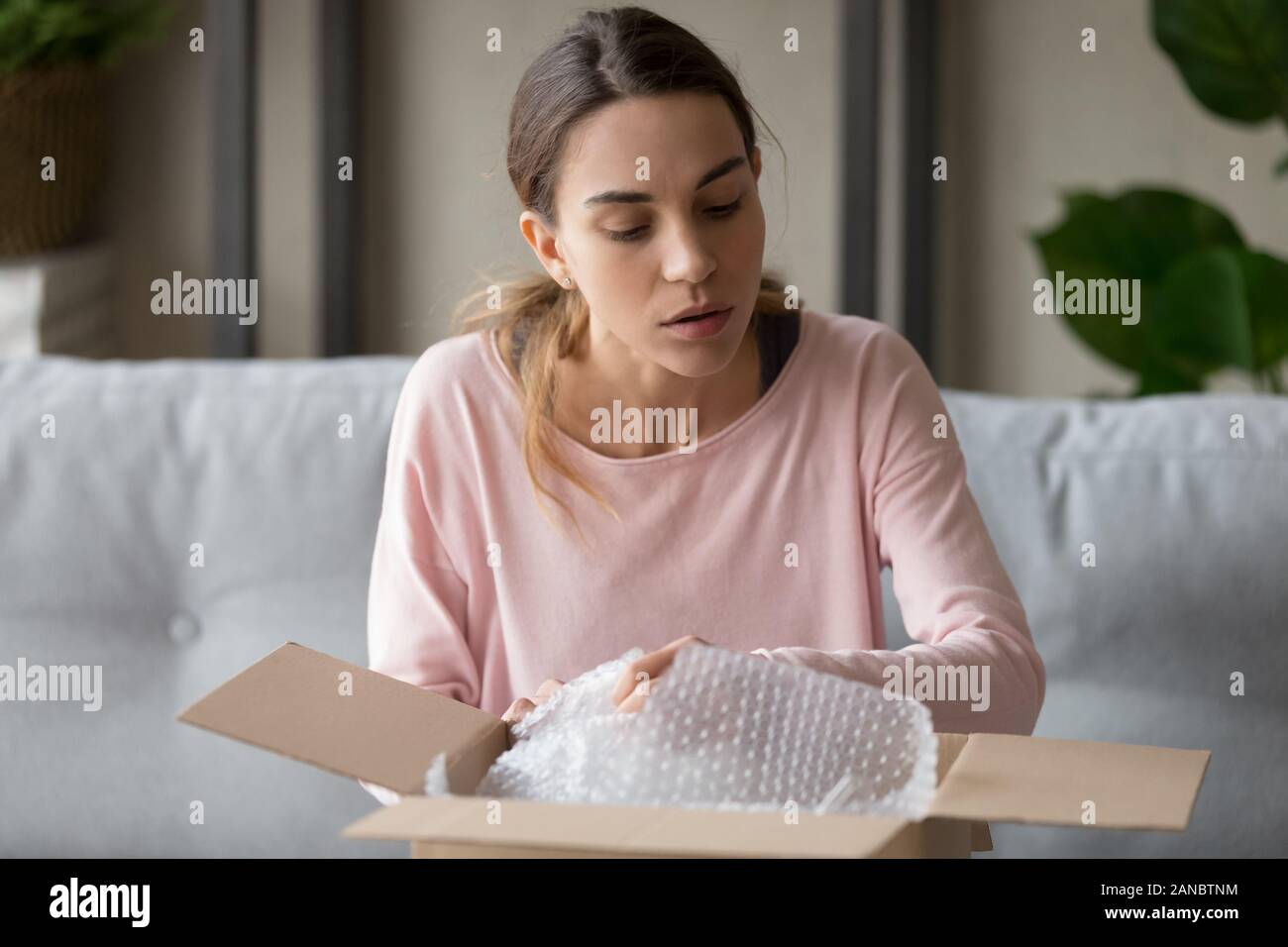 Millennial girl unpacking parcel with fragile things Stock Photo - Alamy