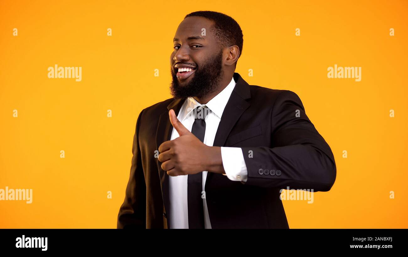 Smiling black man in business suit in suit making thumbs-up and looking ...