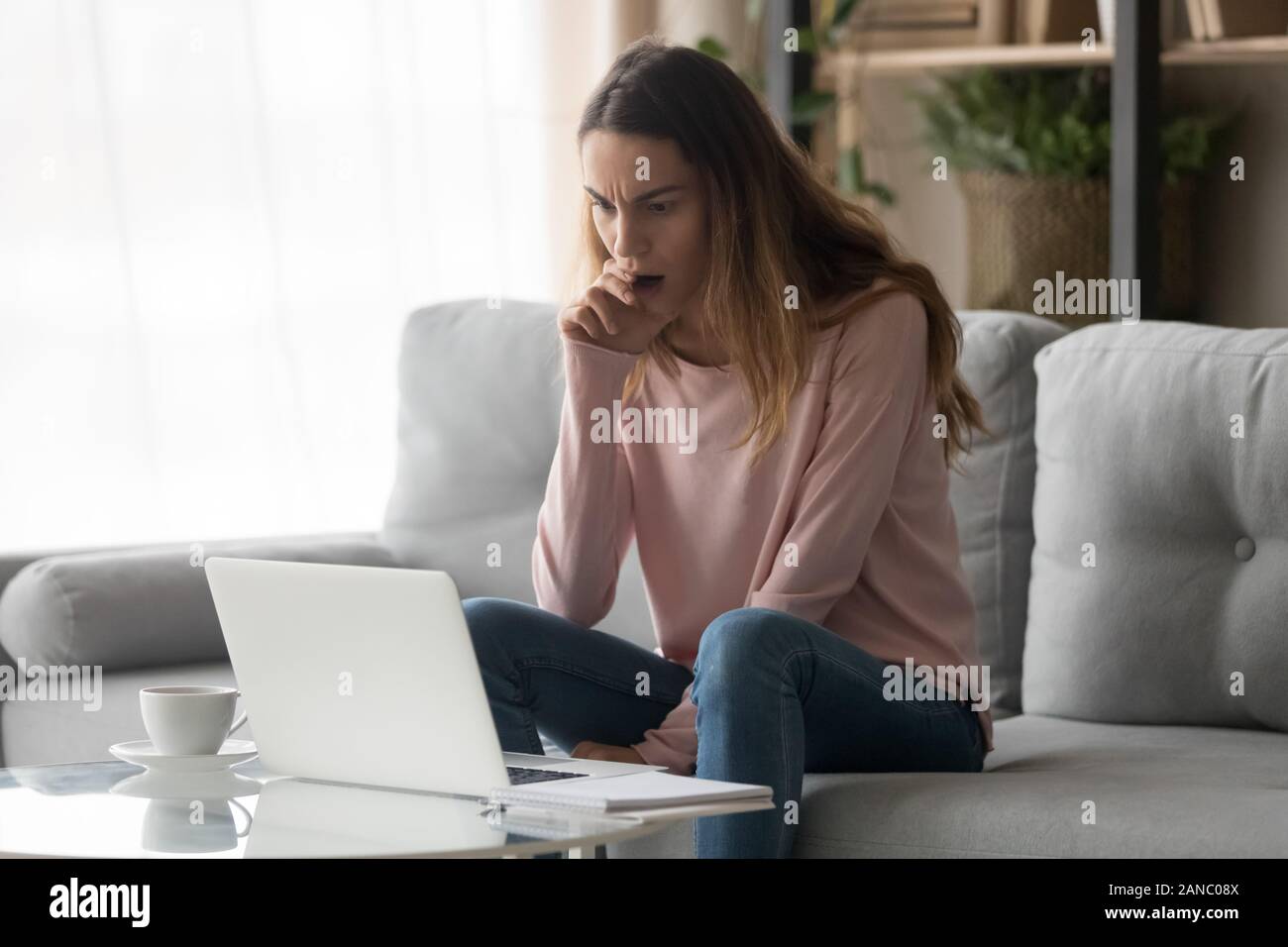Negatively surprised frowning young lady irritated by computer problem ...