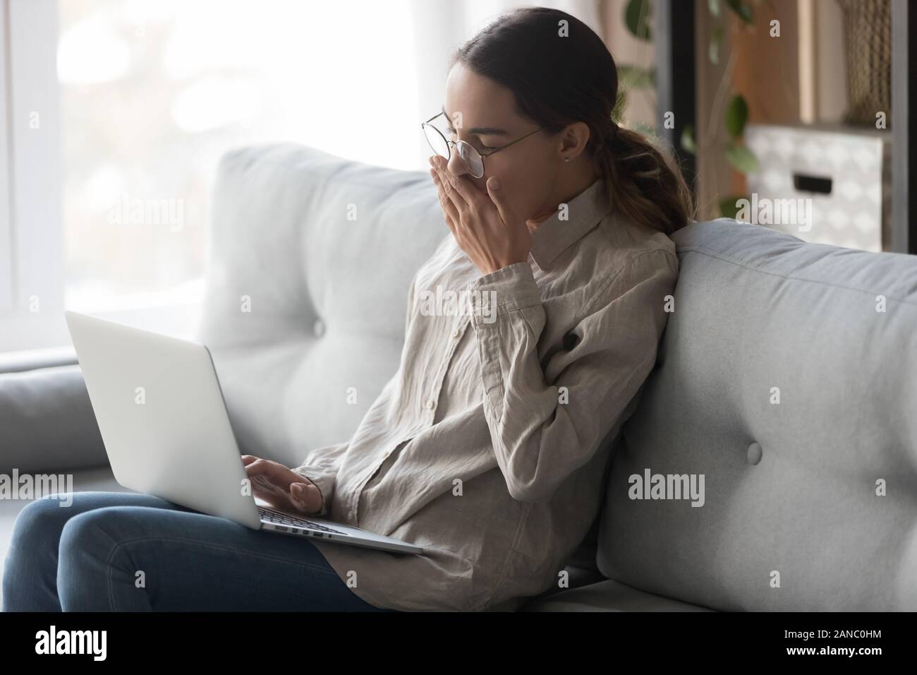 Young tired woman yawning, feeling sleepy while working with computer ...