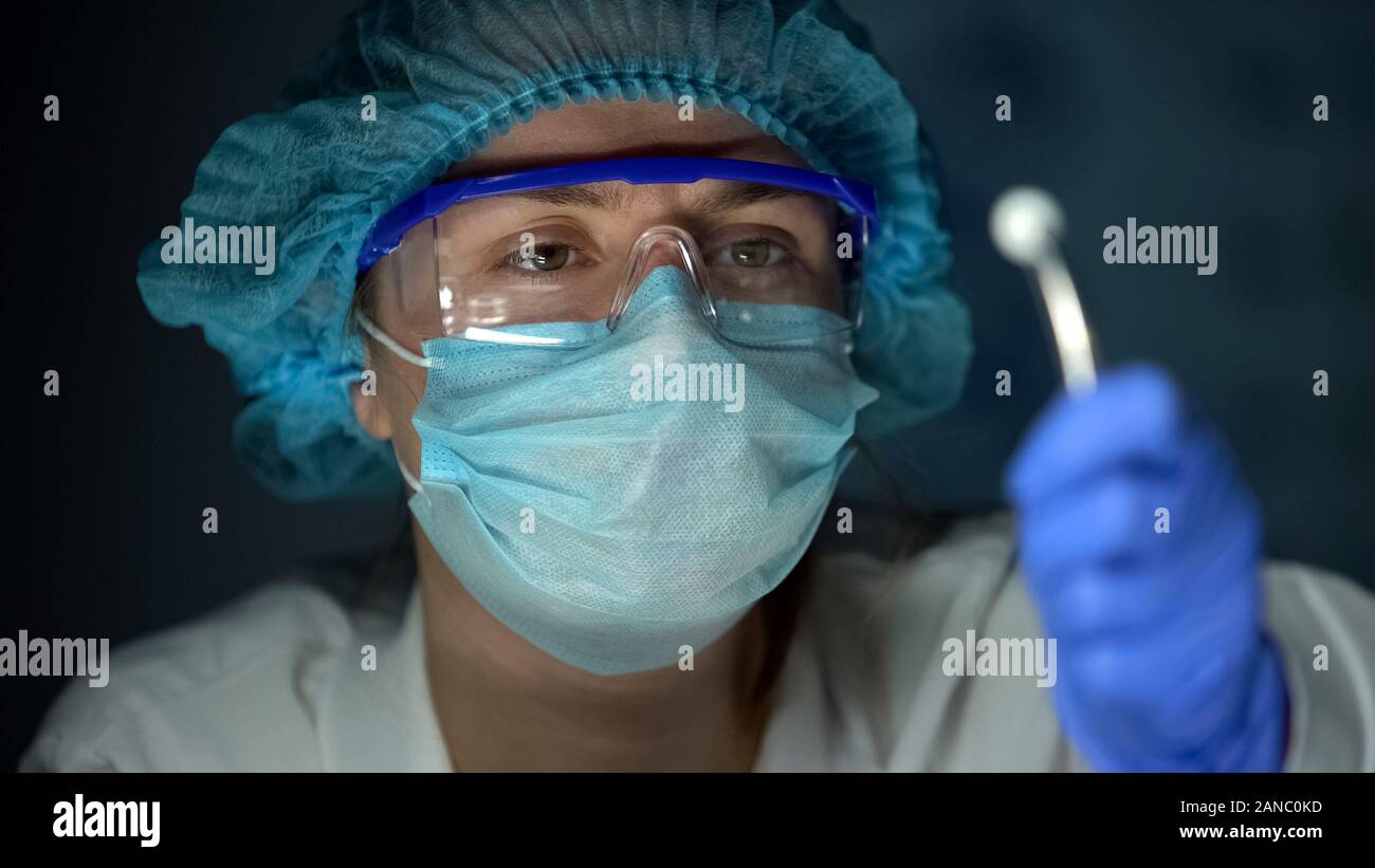 Researcher examining tablet, holding it in forceps, medication ...