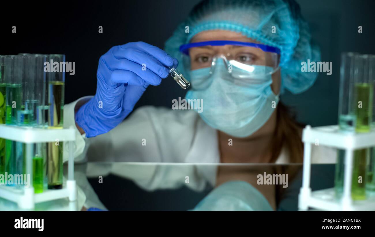 Researcher taking ampule with transparent liquid, antitoxin studies ...