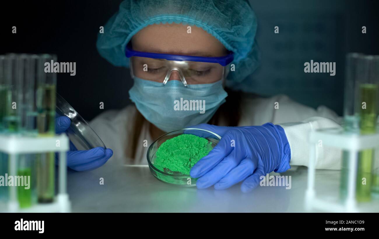 Lab worker opening Petri dish with green powder, cosmological ...
