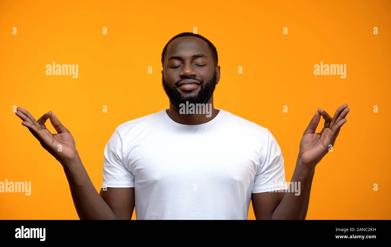 Pacified black man meditating against yellow background, breathing ...