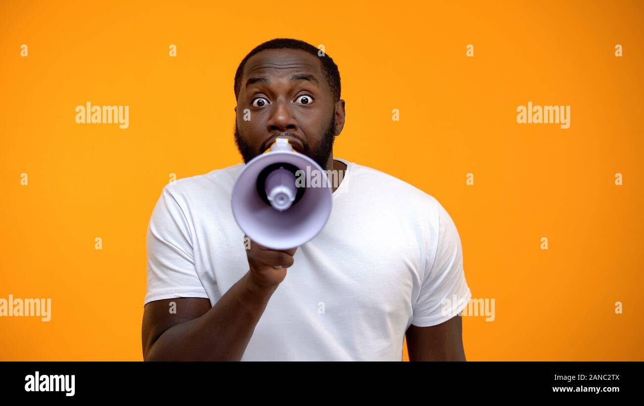 Frightened black man screaming in megaphone, spreading information ...