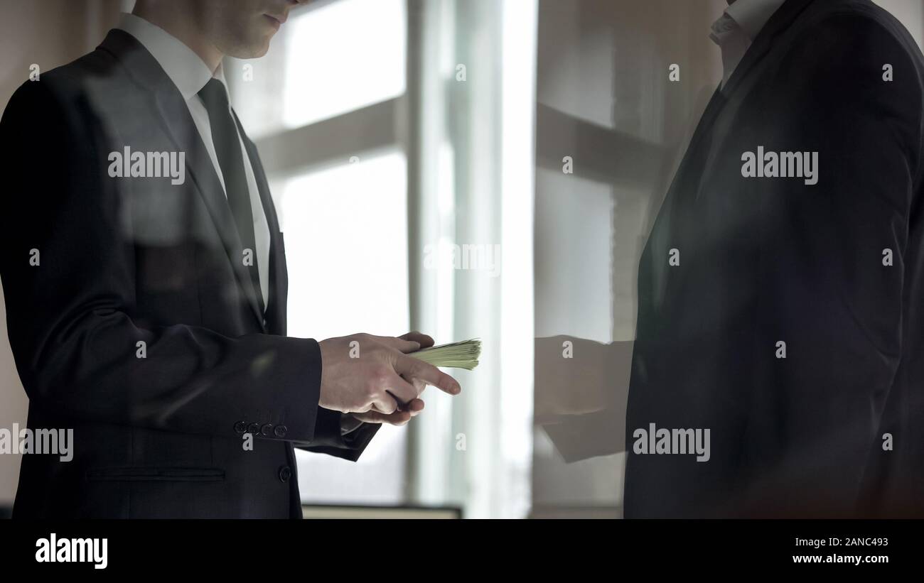 Businessman giving money to partner, profit from successful business ...