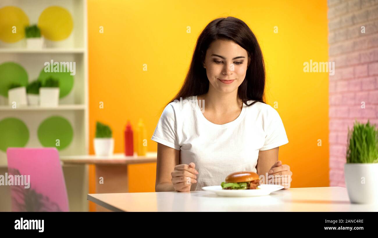 Beautiful female looking at tasty burger, breakfast in fast food ...
