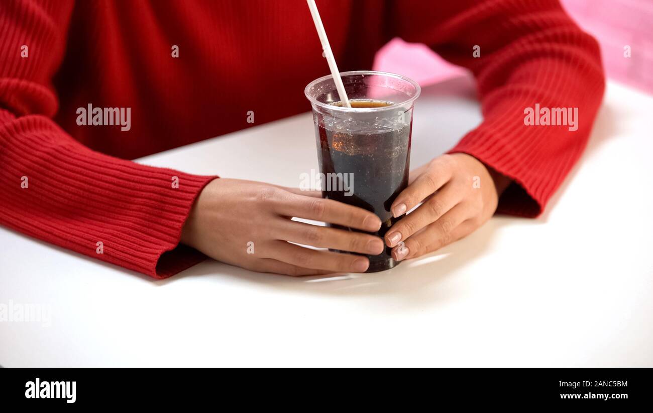 Female customer tasting soft drink from plastic glass through straw ...