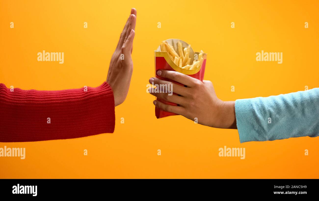 Female hand showing stop gesture on yellow background, refusing eat ...