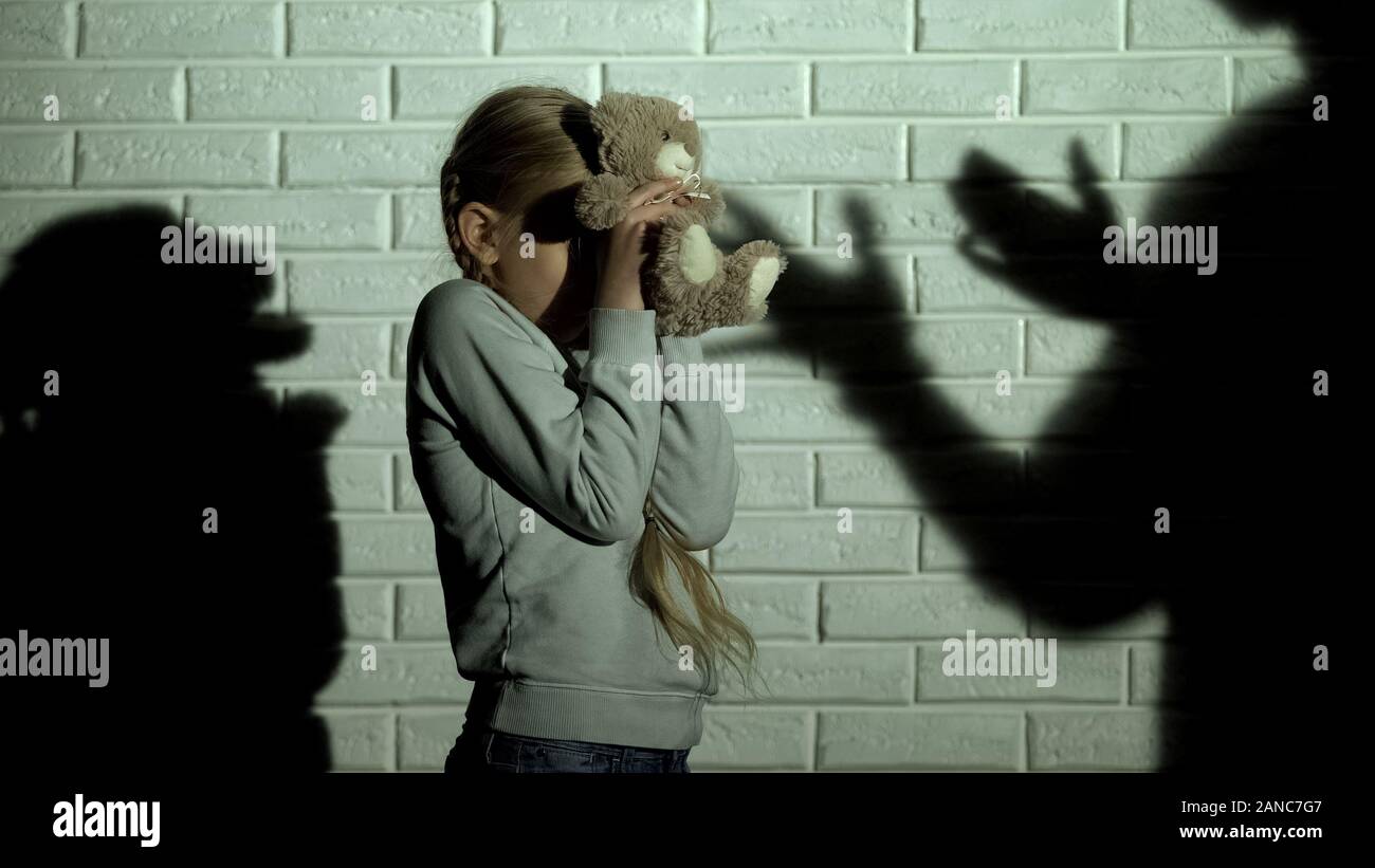 Scared kid with teddybear, shadow of adult screaming at child, domestic ...