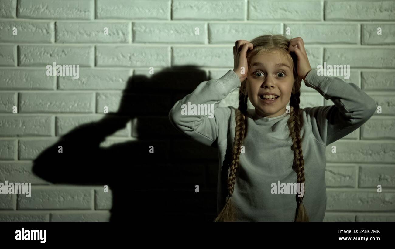 Scared child touching head, looking at camera, fear and horror concept ...