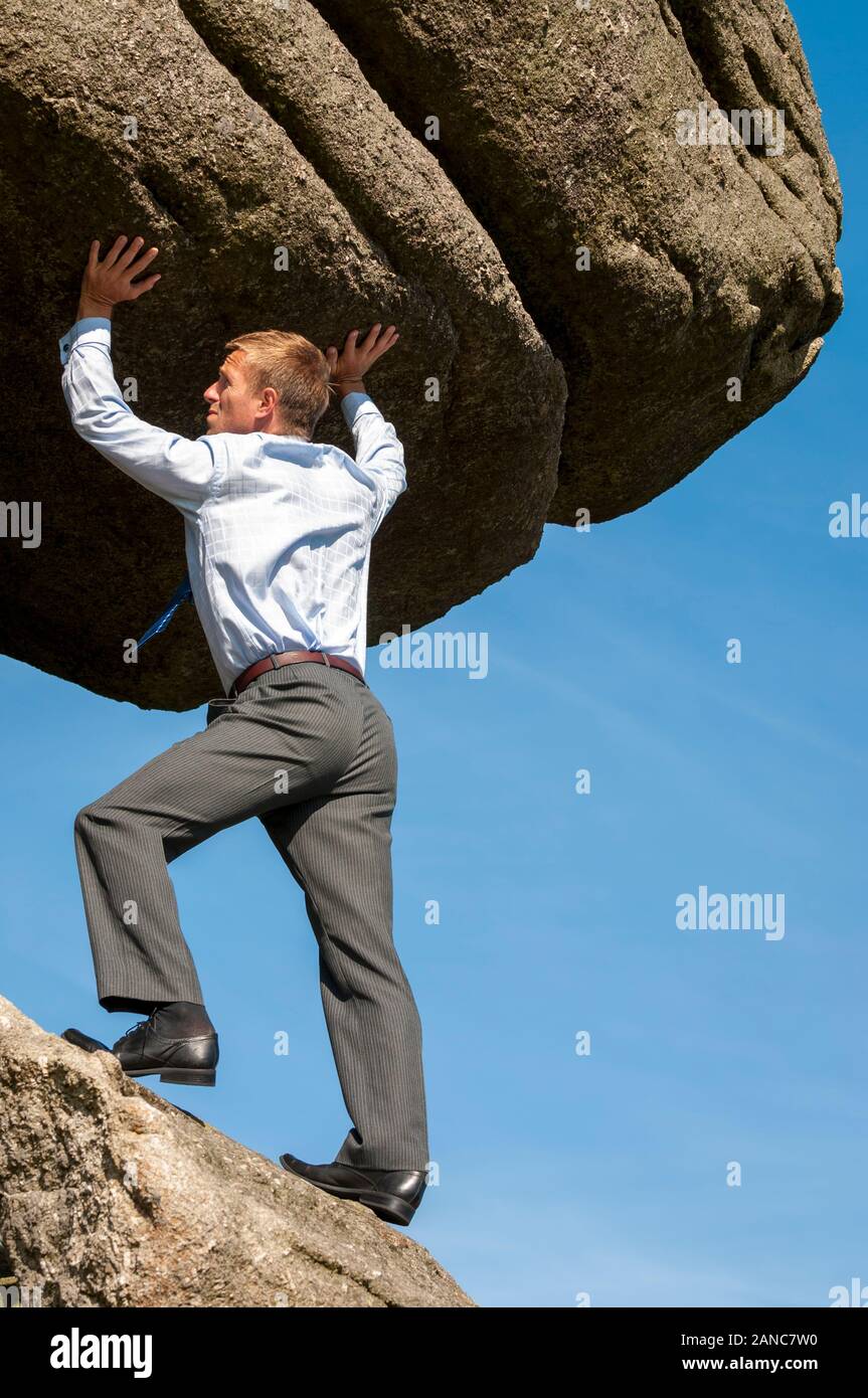 Strong businessman struggling to lift massive boulder into blue sky ...