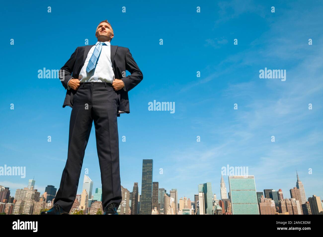Giant businessman standing tall in dark suit above the city skyline ...