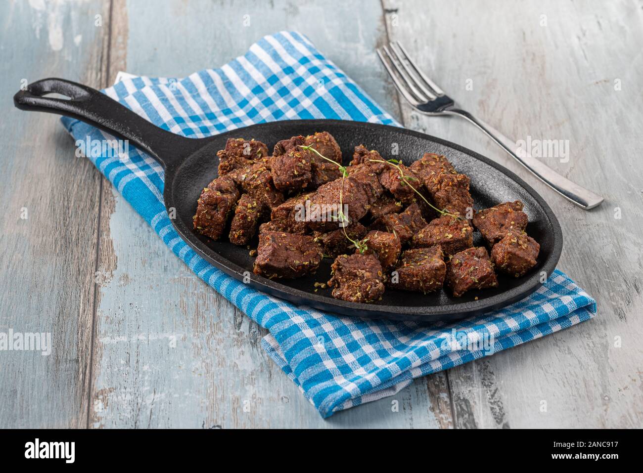 Fried liver cubes in black griddle on wooden background Stock Photo - Alamy