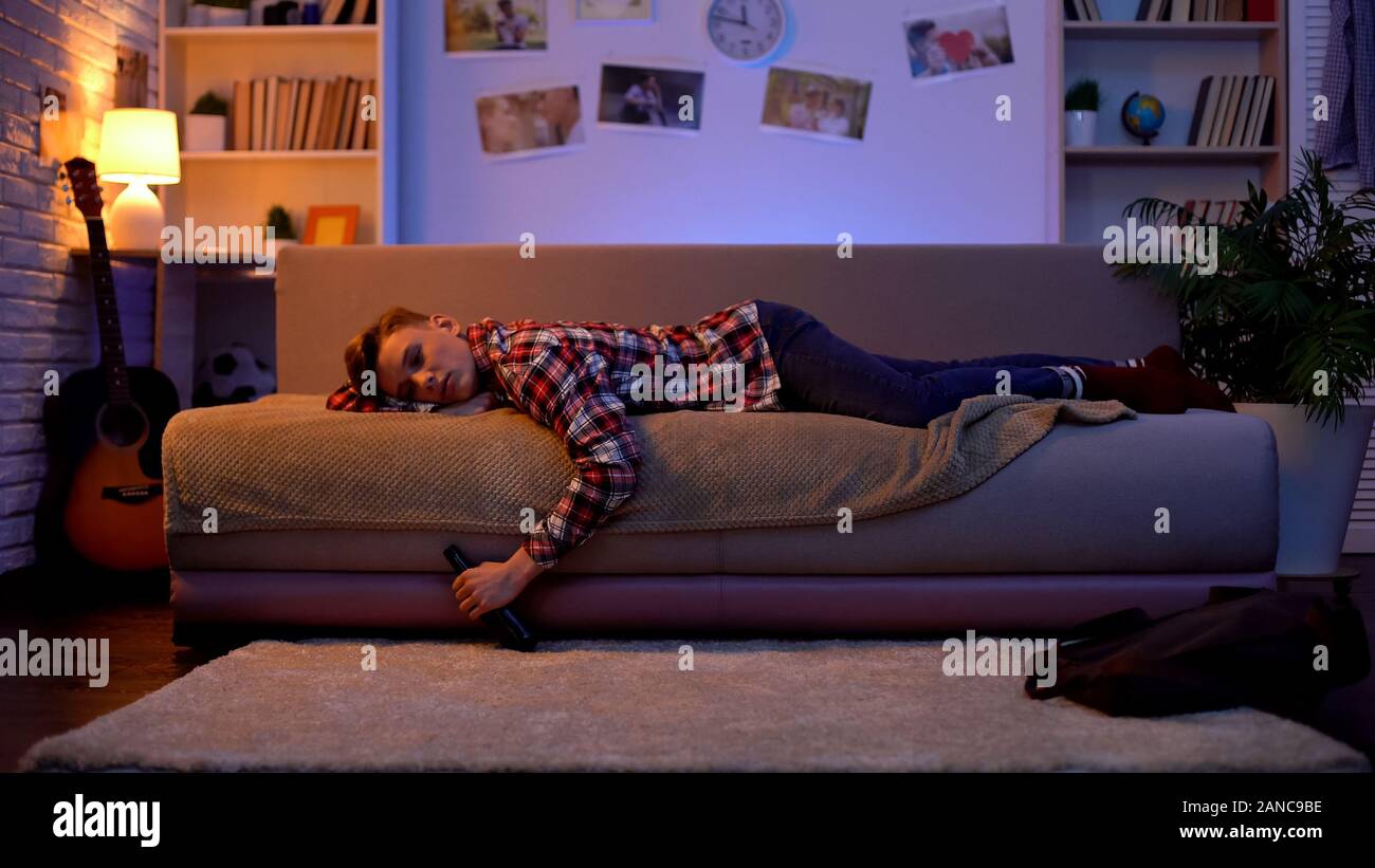 Drunk teenager sleeping on couch holding bottle of beer, alcohol ...