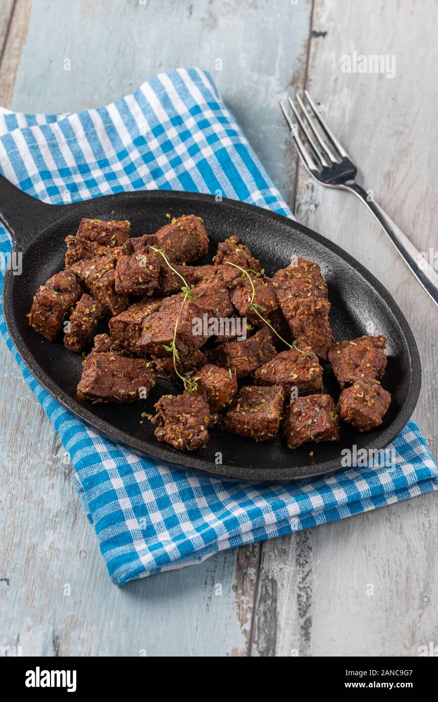 Fried liver cubes in black griddle on wooden background Stock Photo - Alamy