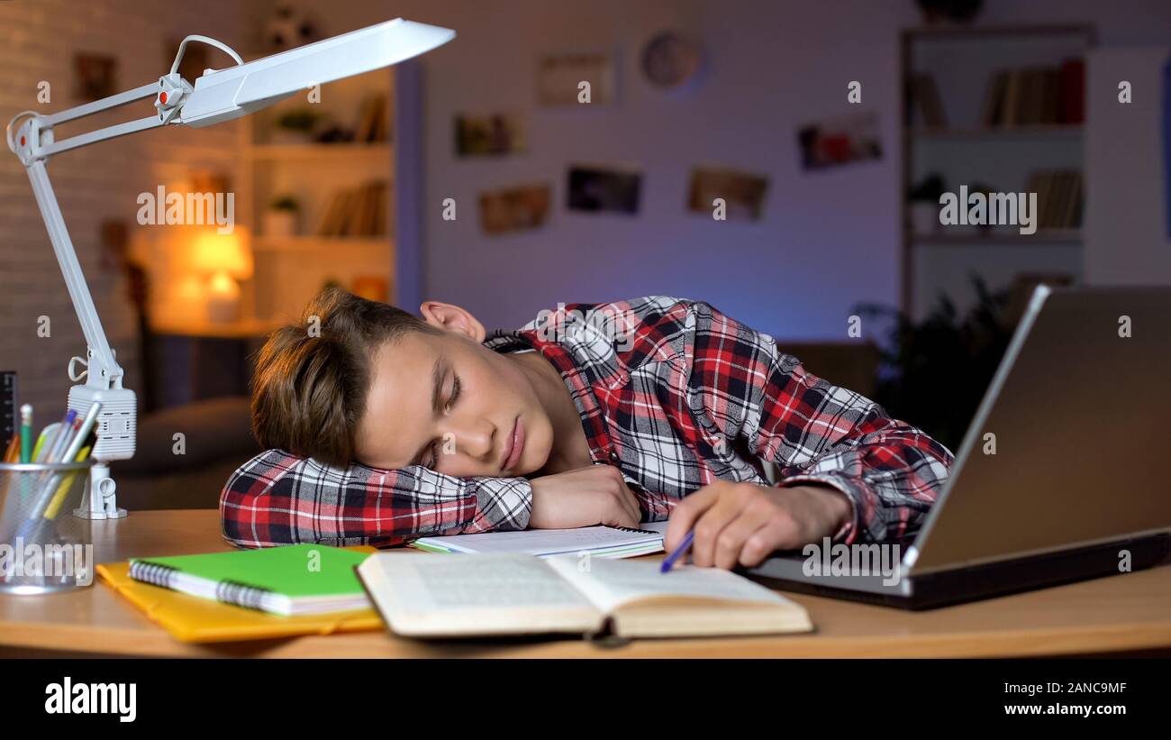 Extremely tired student sleeping by table on pile of books, overloaded ...