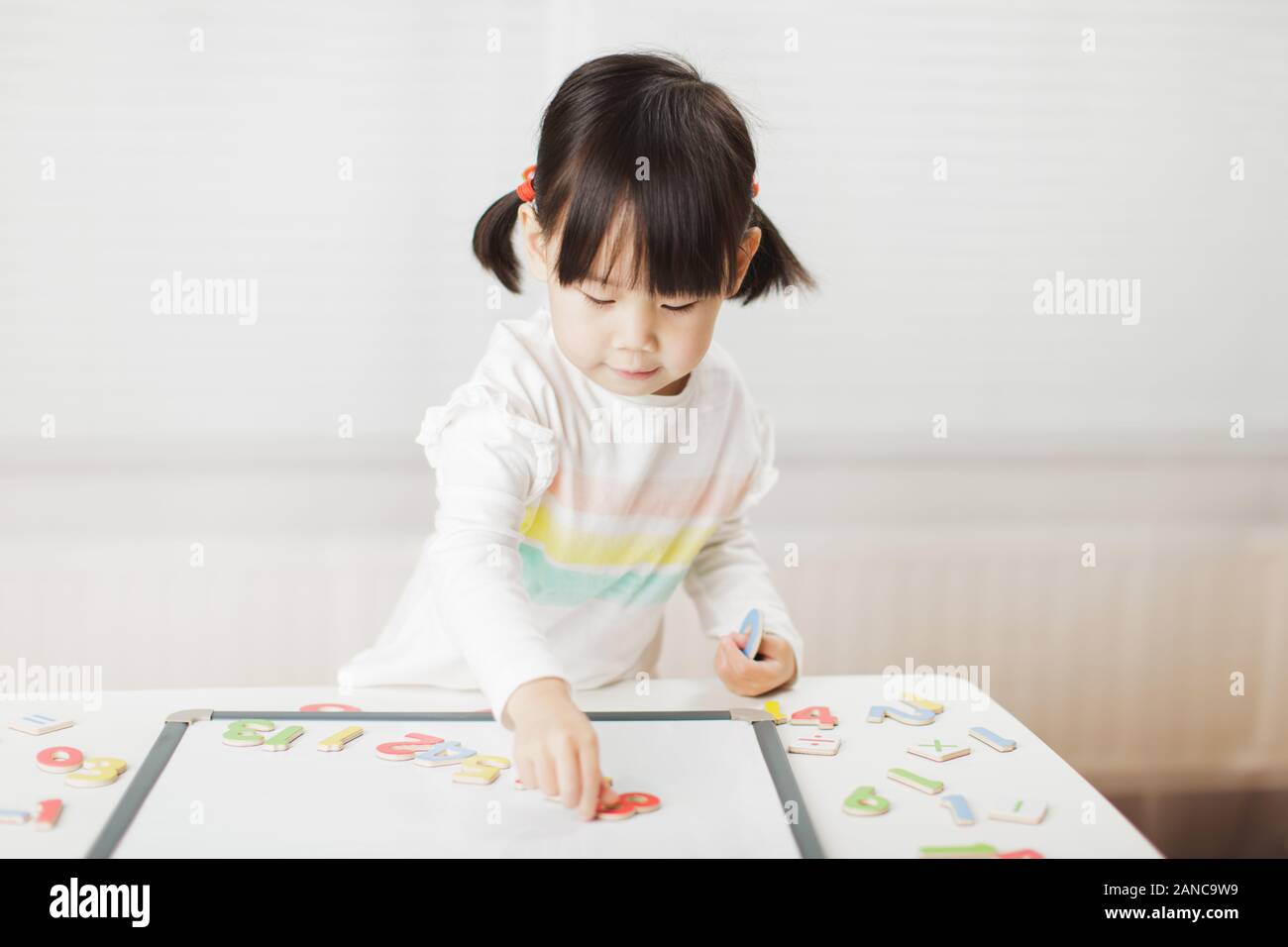toddler girl learning math on white board against white background ...