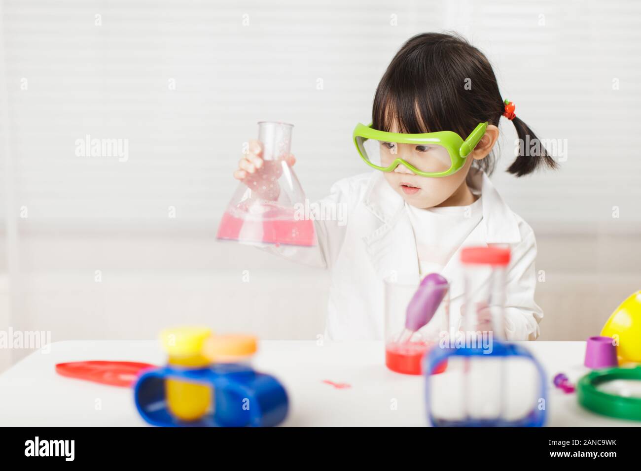 toddler girl pretend play scientist role at home against white ...