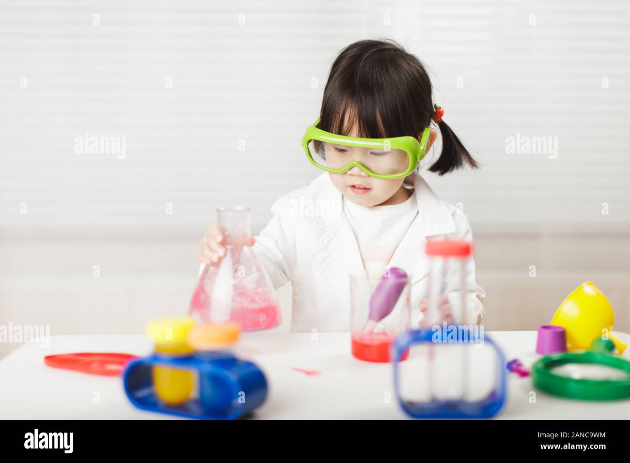 toddler girl pretend play scientist role at home against white ...