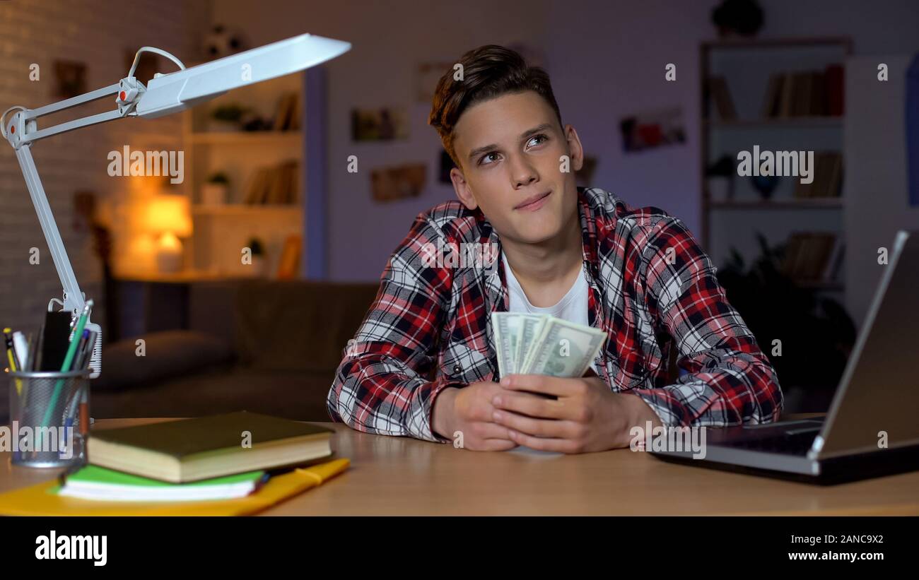 Boy holding lot of cash receiving first salary, thinking about new ...