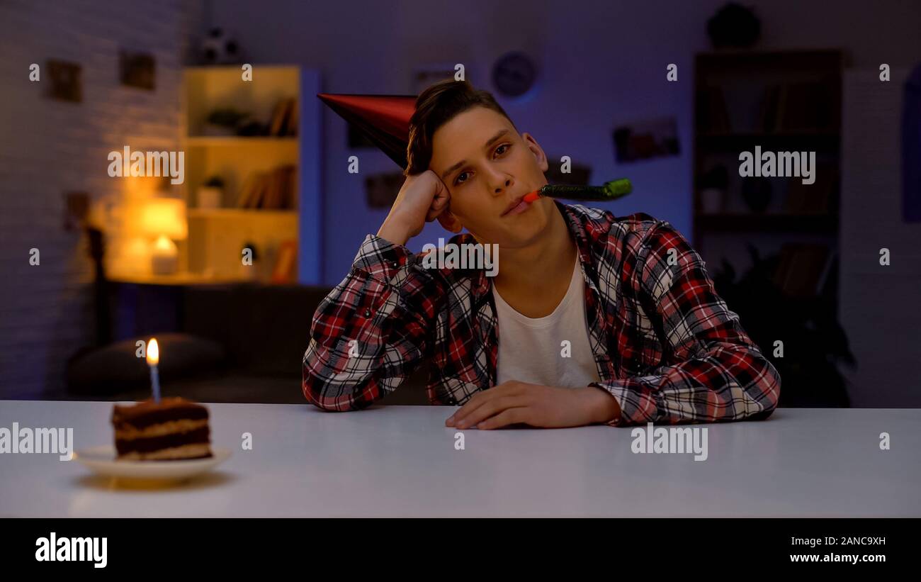 Lonely teenager with party blower and cake celebrating birthday ...