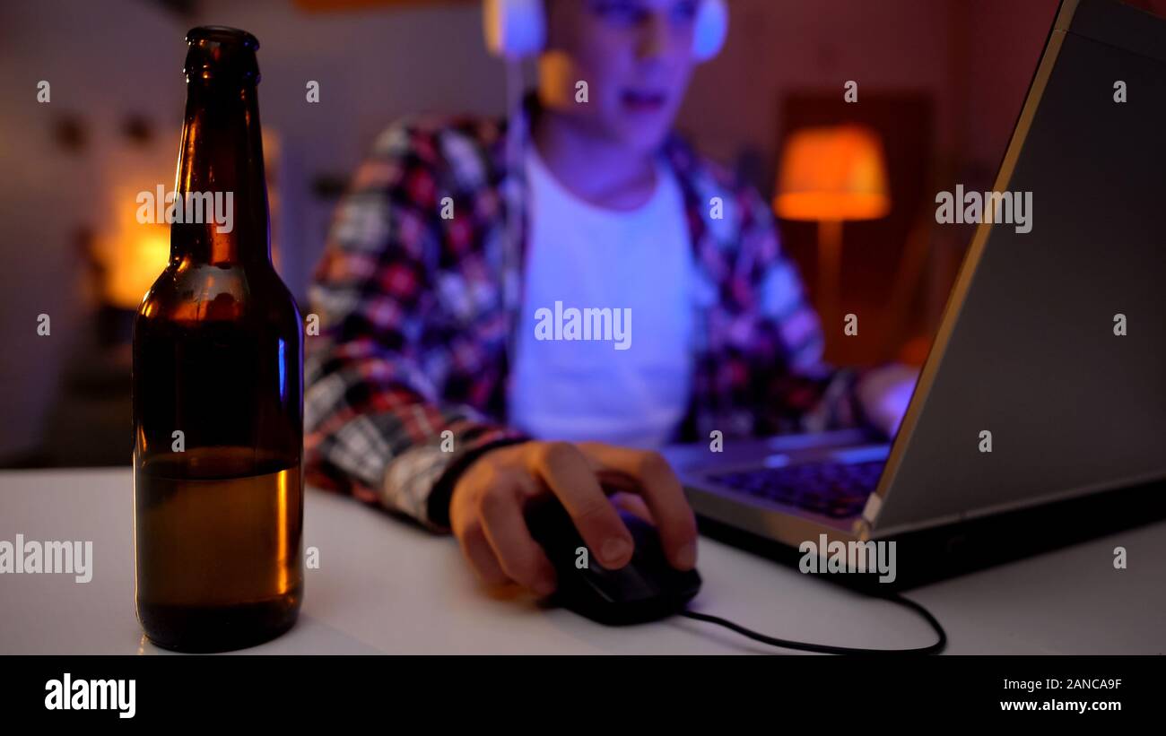 Teenager drinking beer and playing computer games, alcoholism, harmful ...