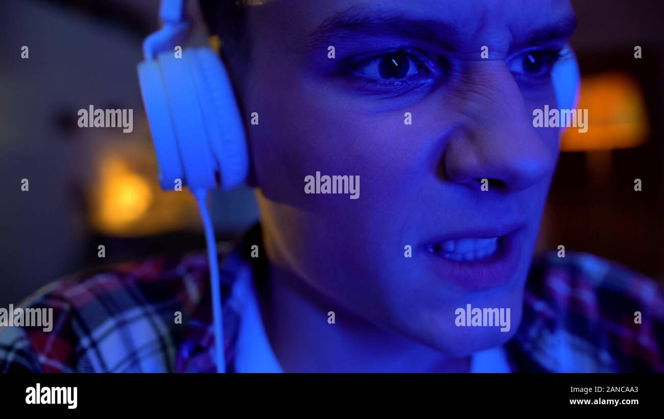 Emotional teenager playing video game night, awkward age, face mimics ...