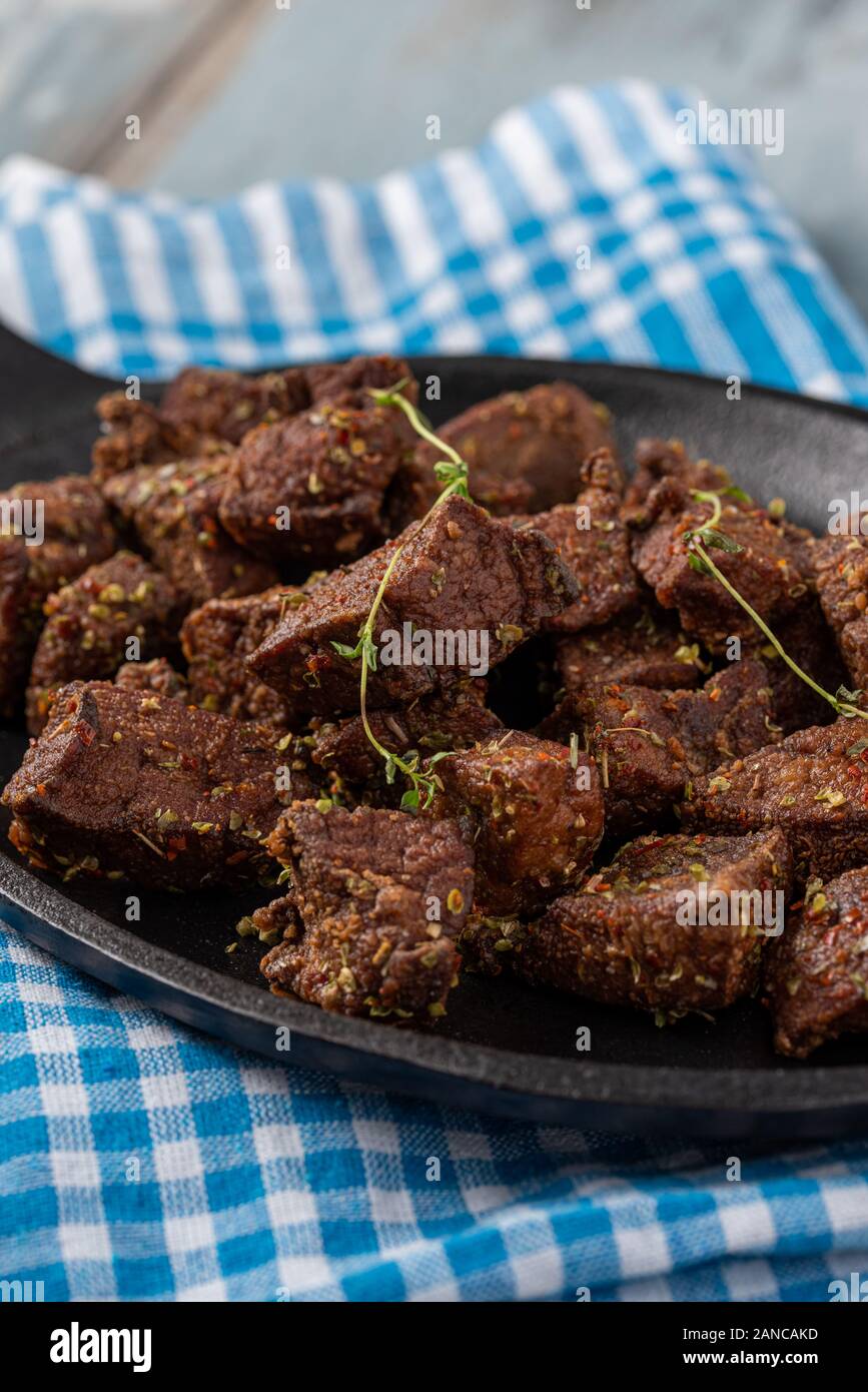 Fried liver cubes in black griddle on wooden background Stock Photo - Alamy