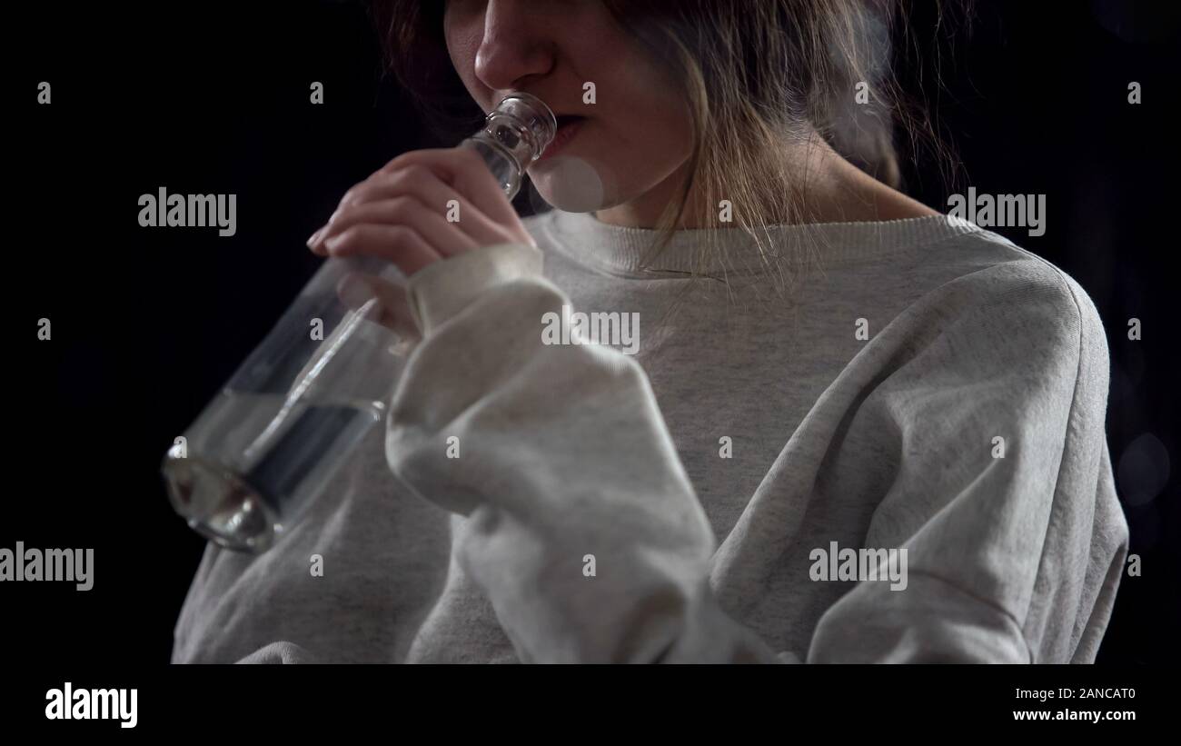 Young woman drinking vodka from bottle, alcohol addiction, miserable ...