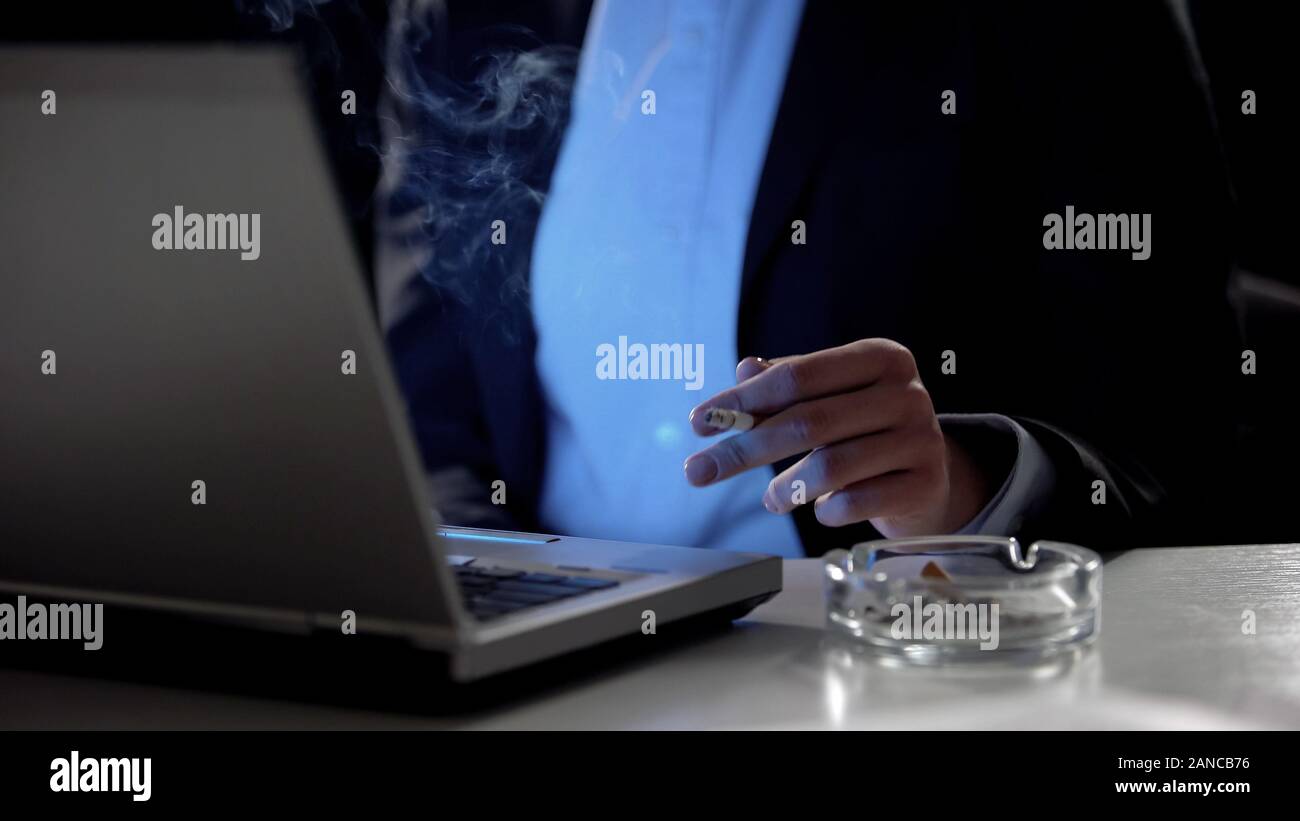 Female manager smoking and working on laptop, stressful job, overwork ...