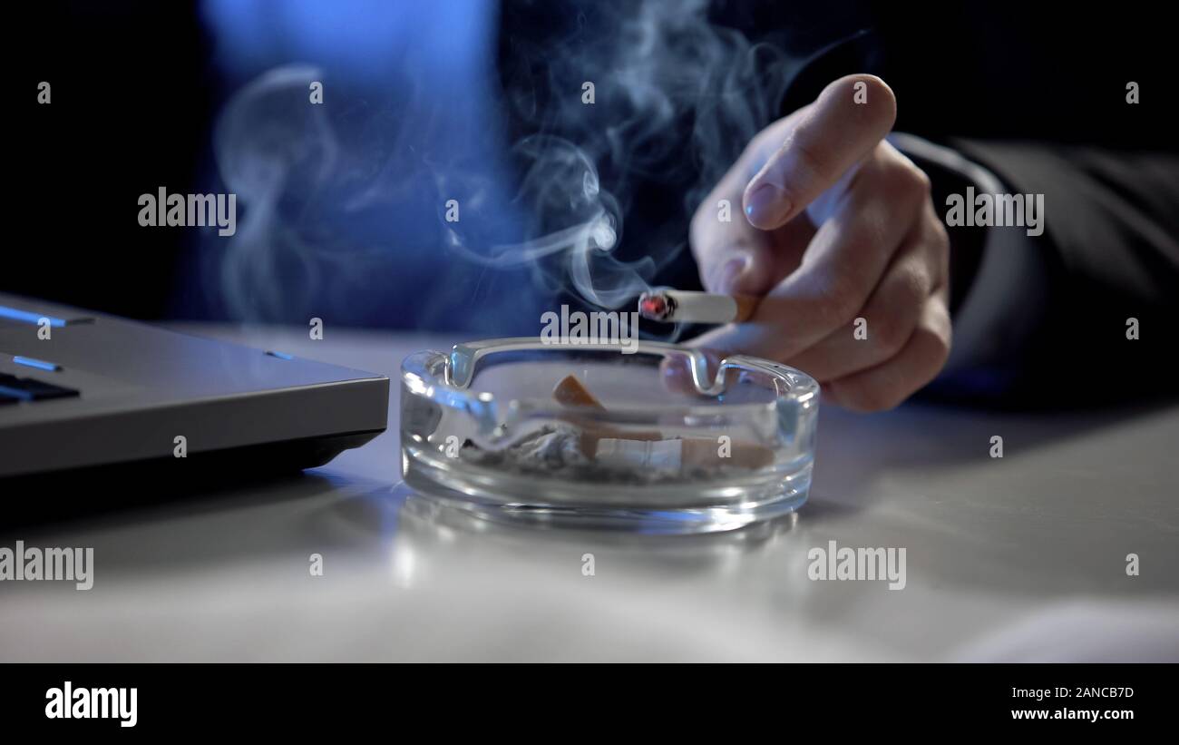 Female hand throwing cigarette ash in tray, smoking at workplace ...