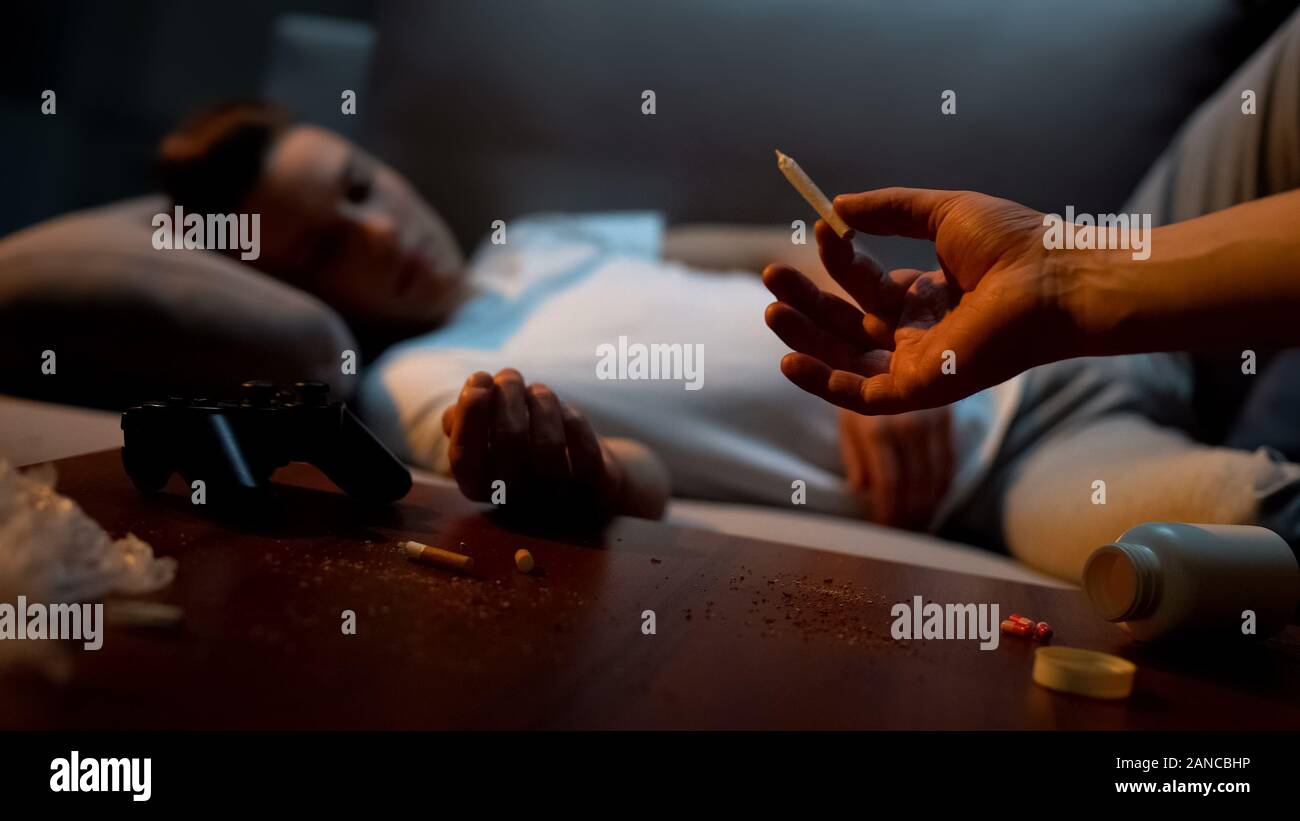Drug dealer hand giving marijuana joint to drug and gaming addicted ...