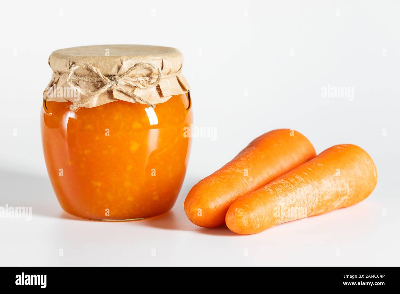 Juicy homemade carrot jam in glass jars on a white background. Side ...