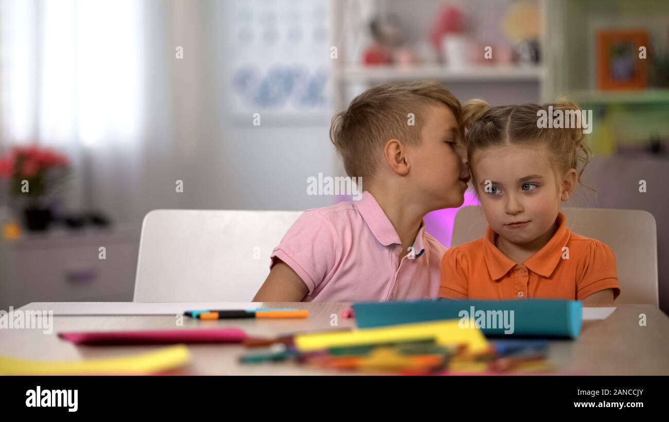 Brother whispering secret to sisters ear, children communication ...