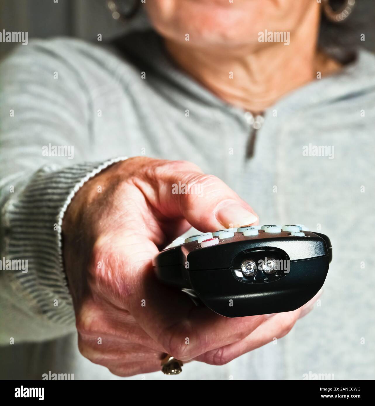 older woman's hand holding tv remote control clicker Stock Photo - Alamy