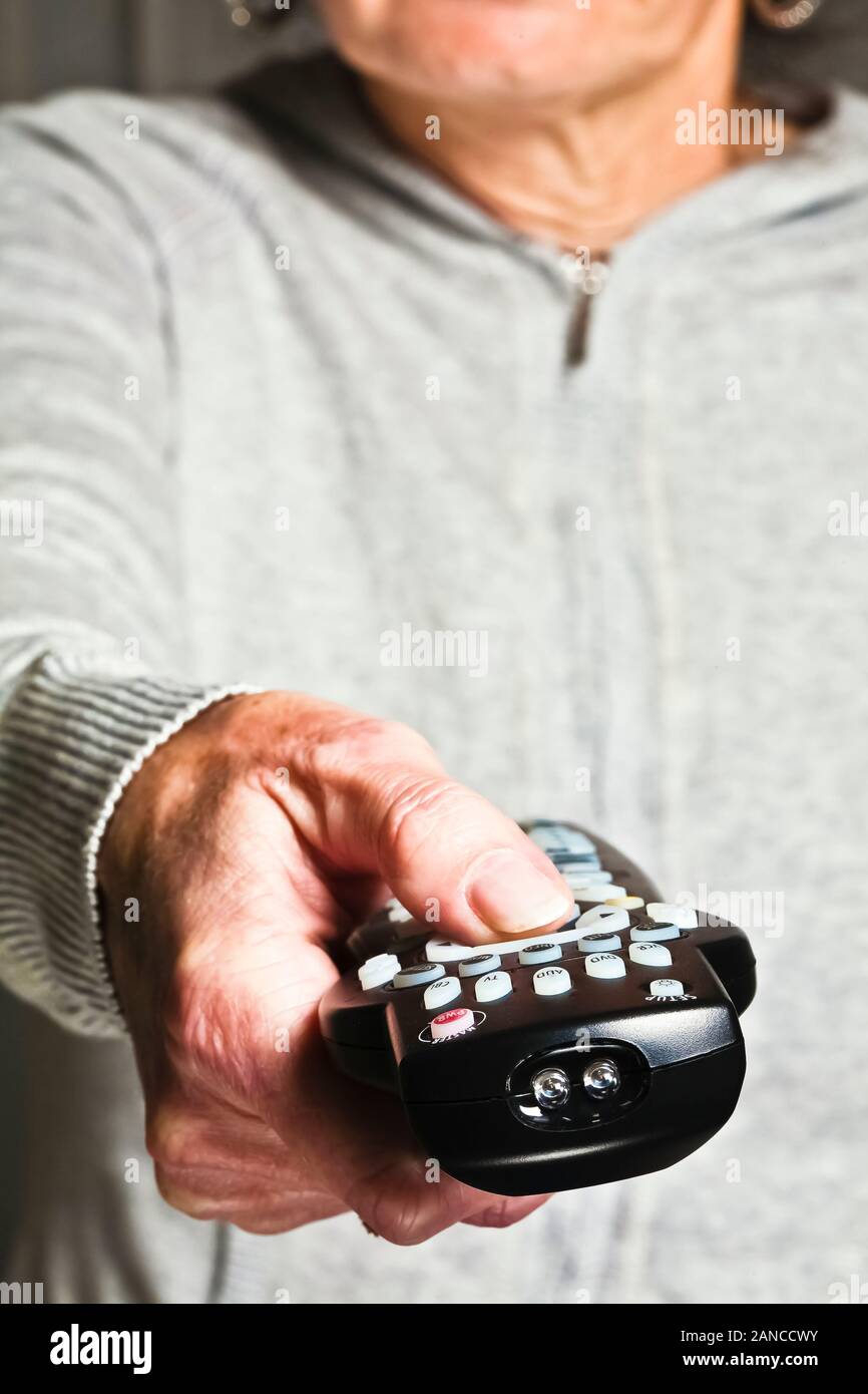 older woman's hand holding tv remote control clicker Stock Photo - Alamy