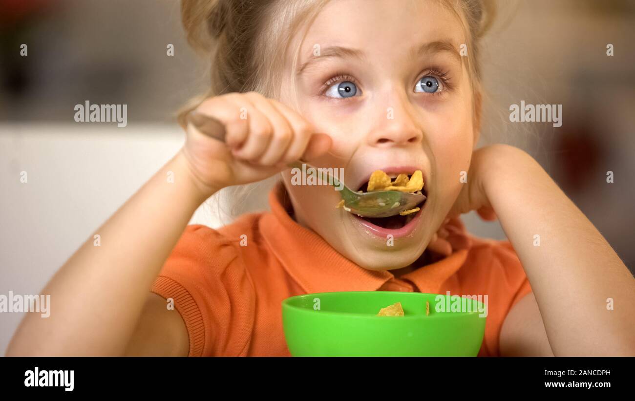 Cute girl eating cereal closeup, appetizing breakfast, morning corn ...