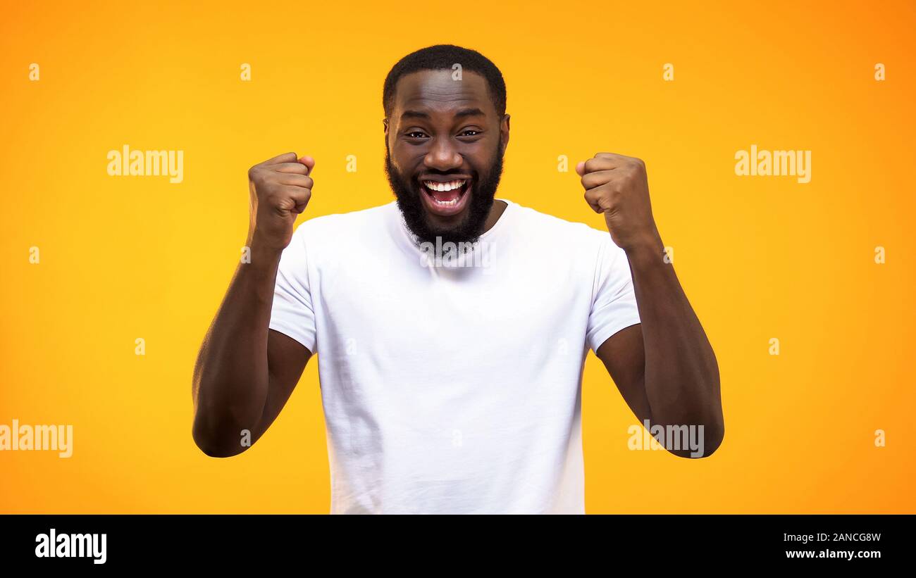 Happy male winner in white t-shirt showing success gesture, achievement ...