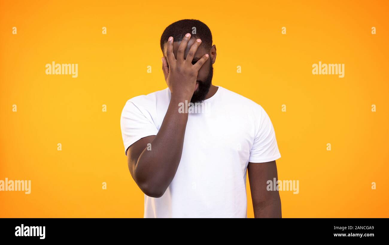 Disappointed afro-american male doing face palm gesture on yellow ...