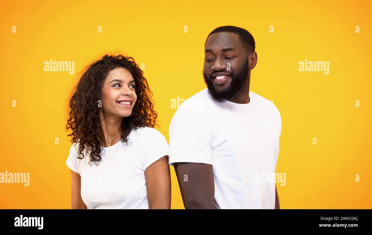 Happy couple flirting and smiling each other on yellow background ...