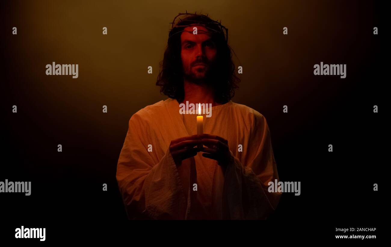 God praying in darkness holding candle, expiation of sins, faith in ...