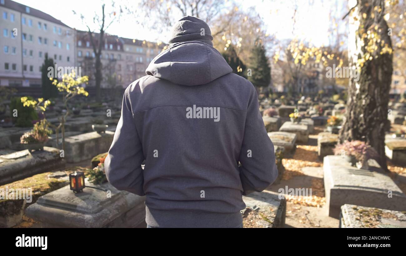 Male walking on cemetery, talking to soul of dead, feeling sorrow and ...