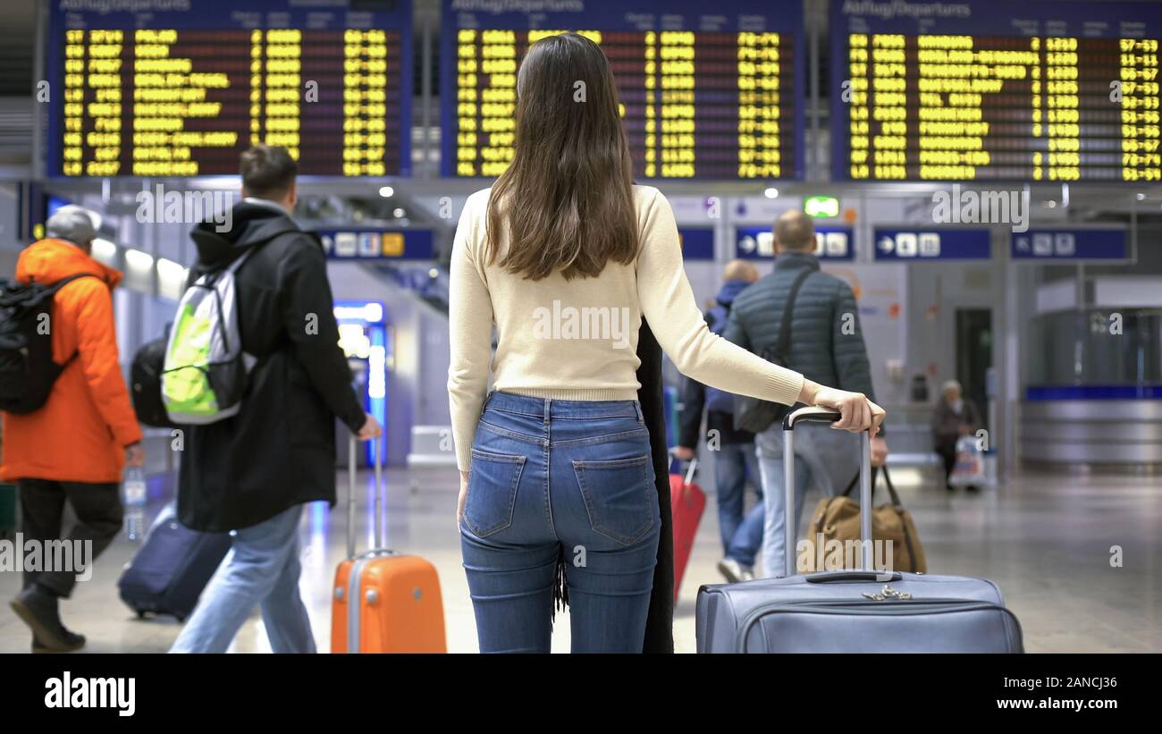 Girl looking at flight arrive and departure board, waiting for check-in ...