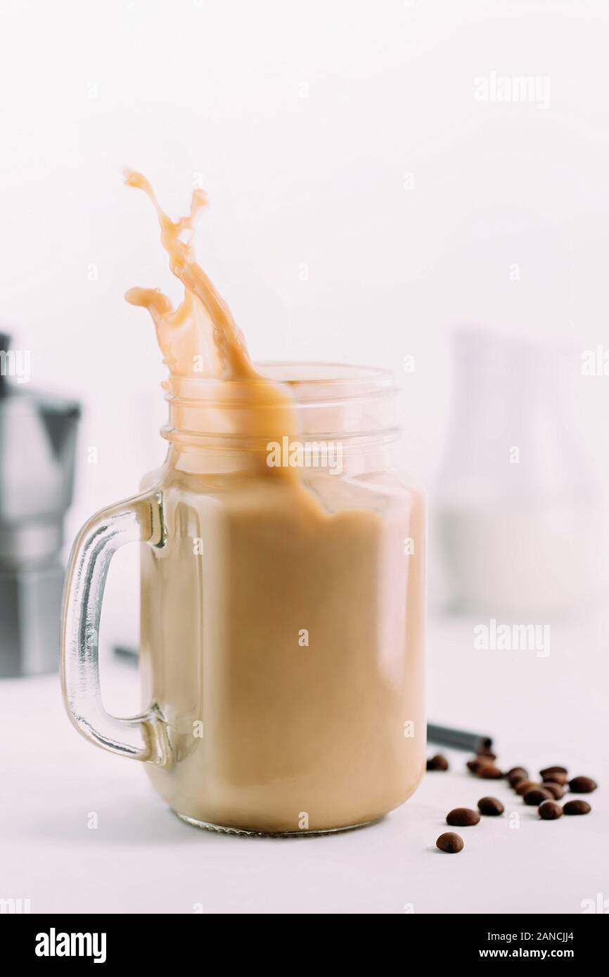 Splash of cold coffee in glass jar and coffee beans Stock Photo - Alamy