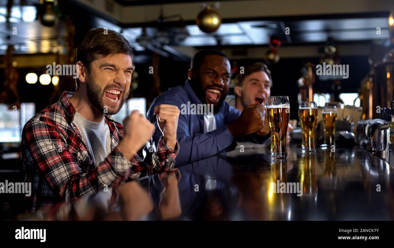Enthusiastic multiethnic men celebrating victory of favorite sports ...