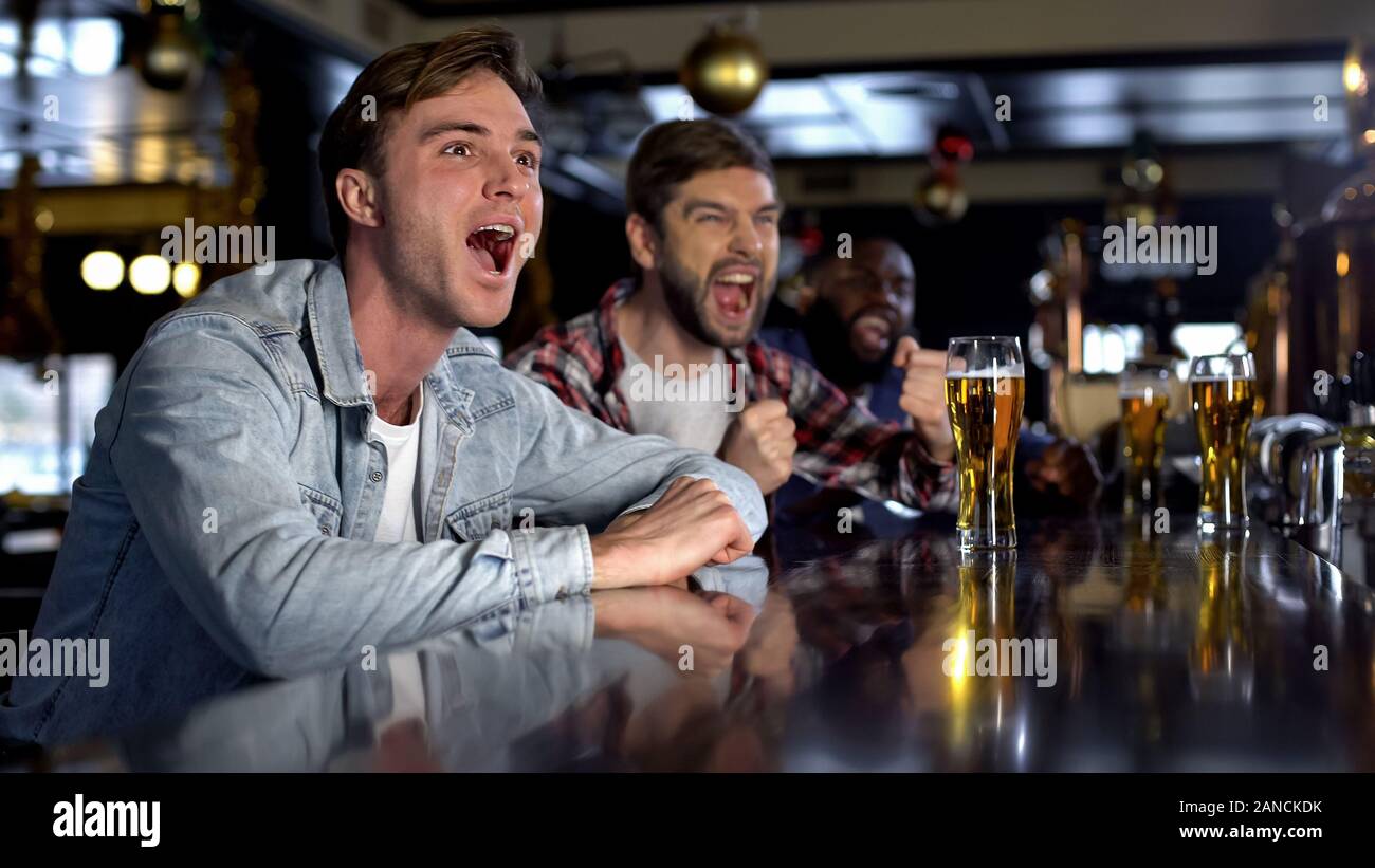 Emotional male fans cheering for favorite team in pub, celebrating game ...